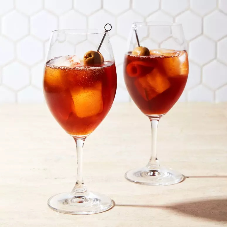 グリーンオリーブとオレンジのピールガーニッシュを添えたパドヴァスプリッツのグラス2杯の写真。