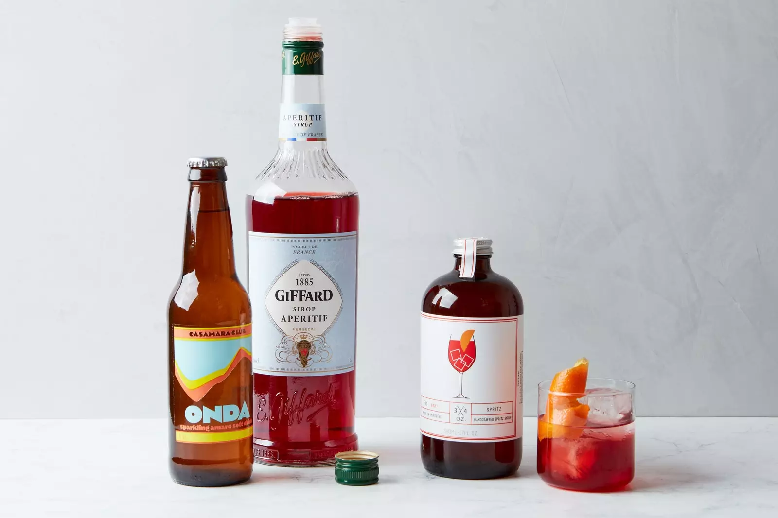 大理石のカウンタートップにボトルのOndaGiffard34とマンハッタンを含む苦い飲み物の写真。