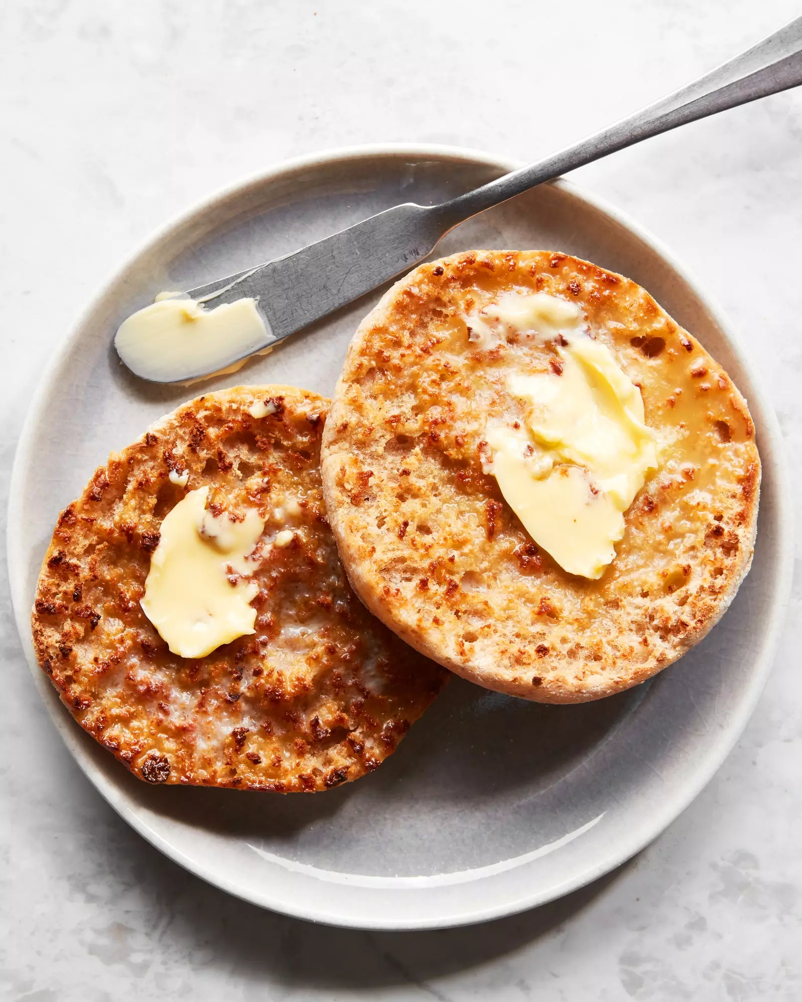 Foto muffin bahasa inggeris sourdough panggang dengan mentega.