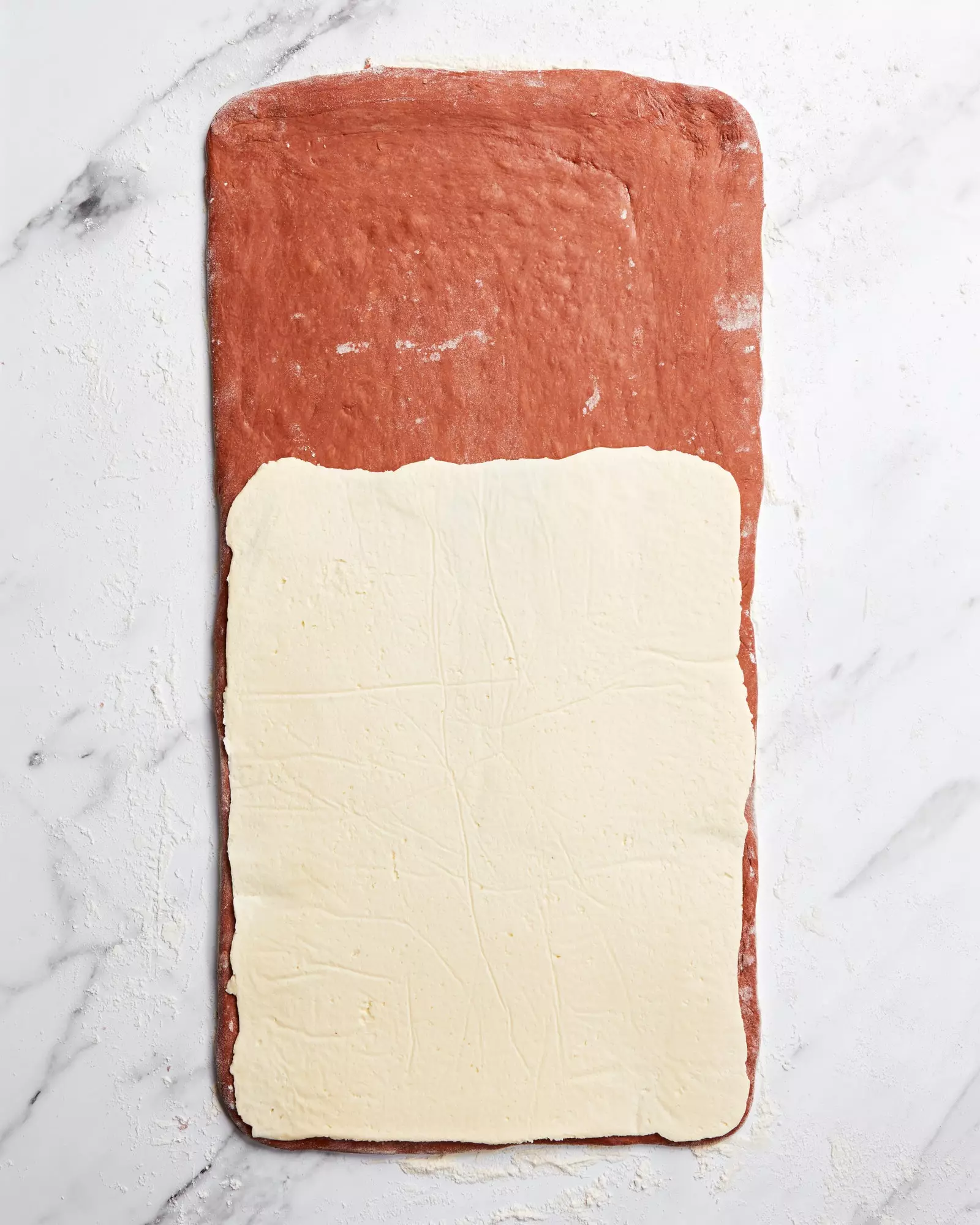 Снимка на тесто за сутрешни кифлички с какао бриош, напълно сгънати върху маслен блок.
