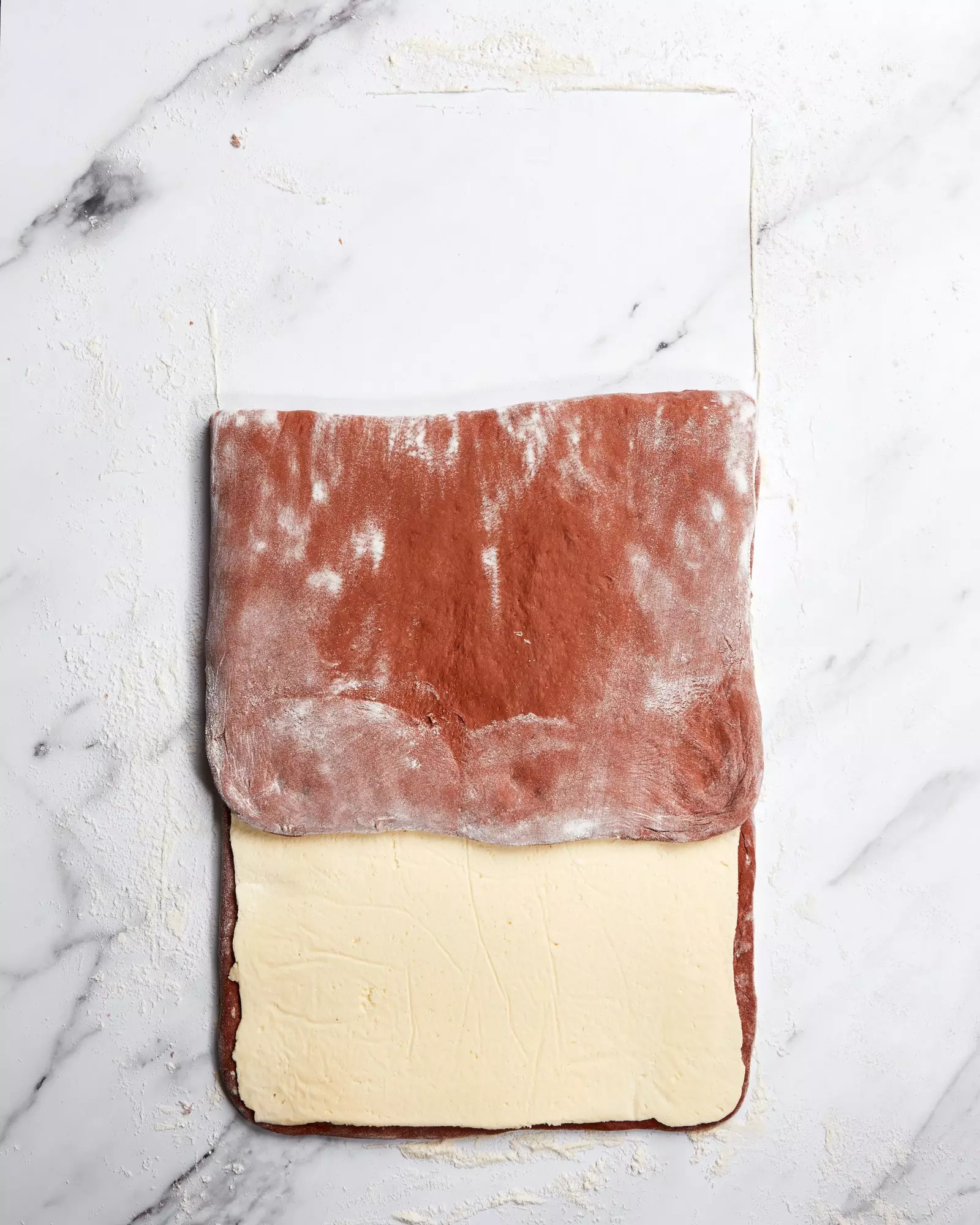 Kakavinių brioche rytinių bandelių tešlos nuotrauka, visiškai sulankstyta ant sviesto blokelio.