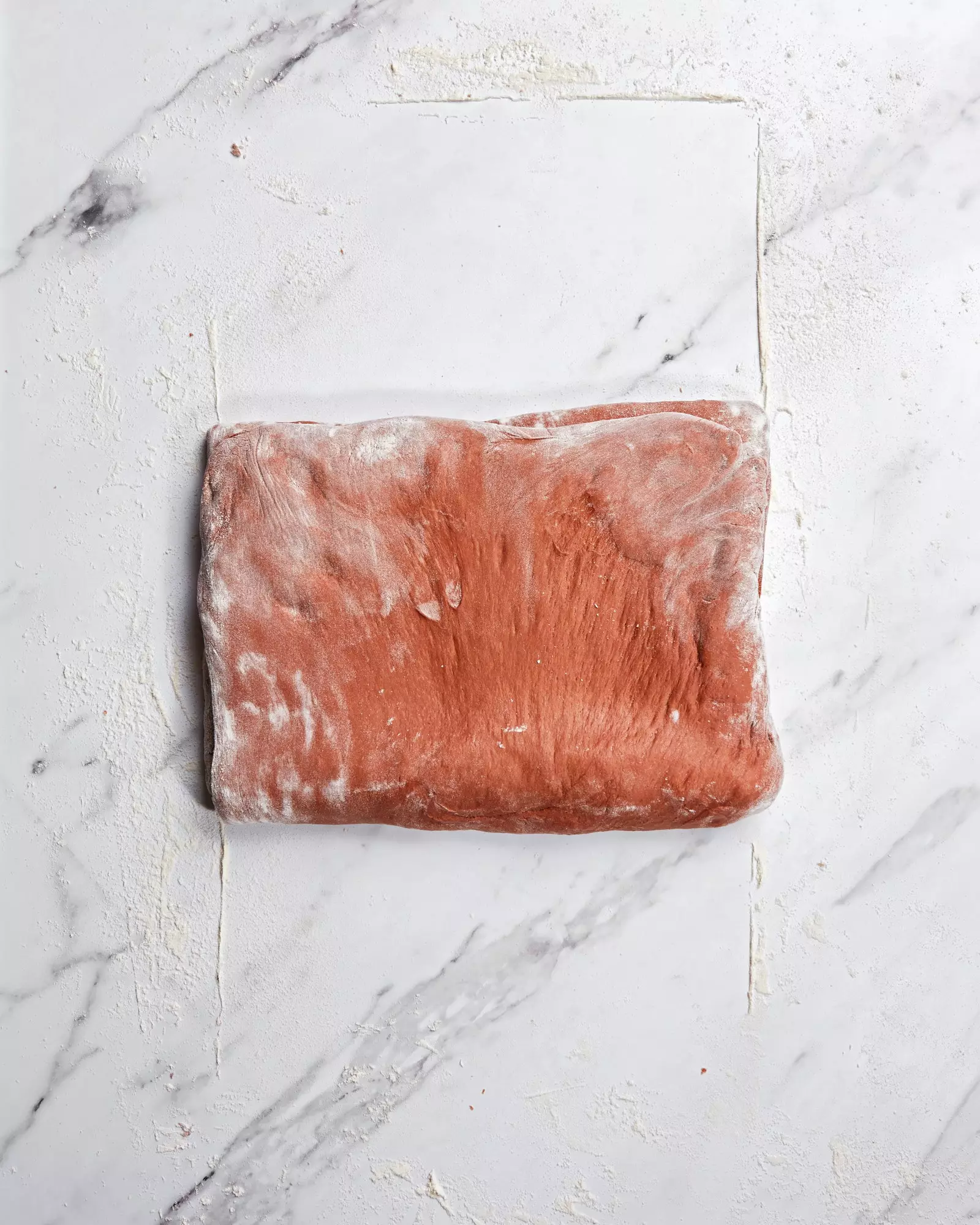 Foto av deig til kakaobroche morgenboller foldet over en smørblokk.
