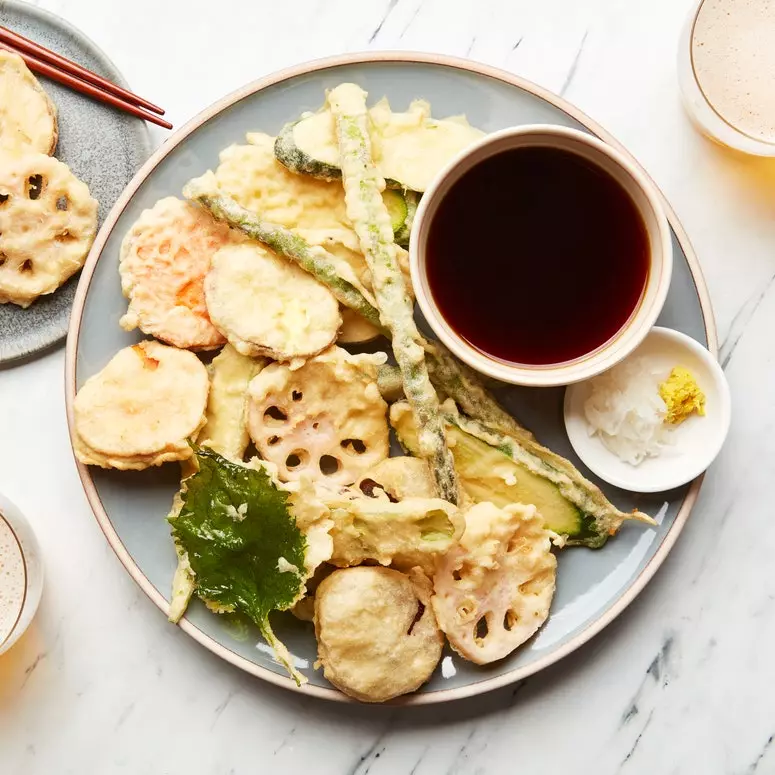 Um prato de tempura de vegetais misturados com molho.