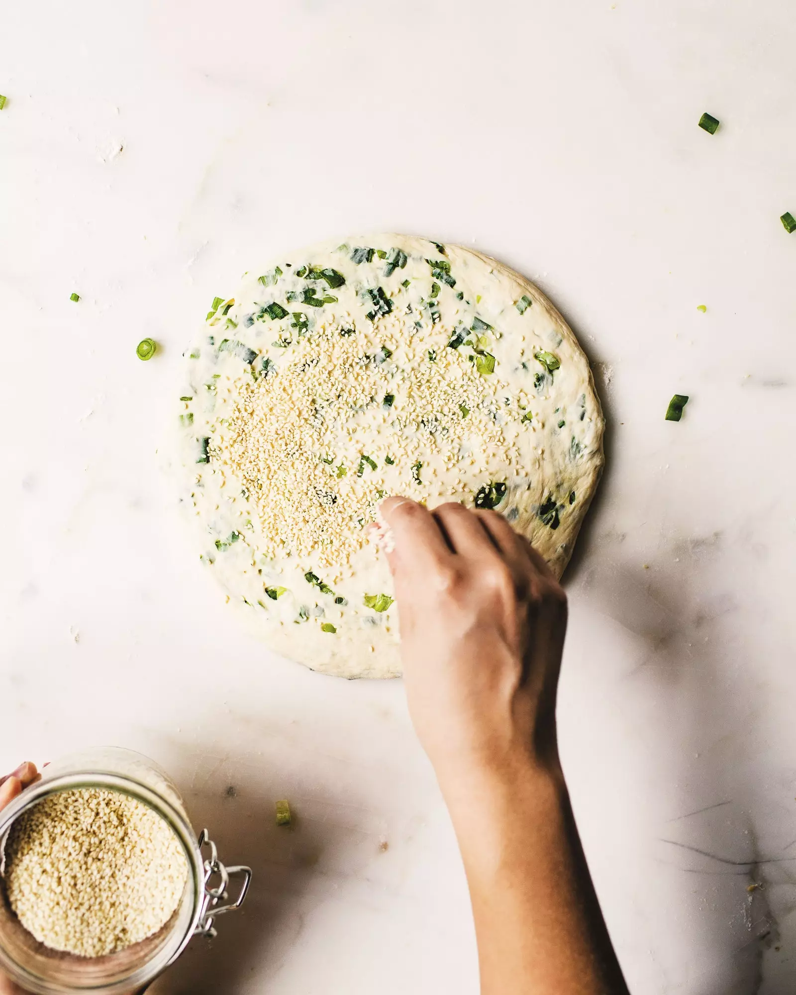 Grianghraf de scallion giosta agus taos Sesame Bing ar countertop marmair le síolta sesame á n-spráil ar a bharr.