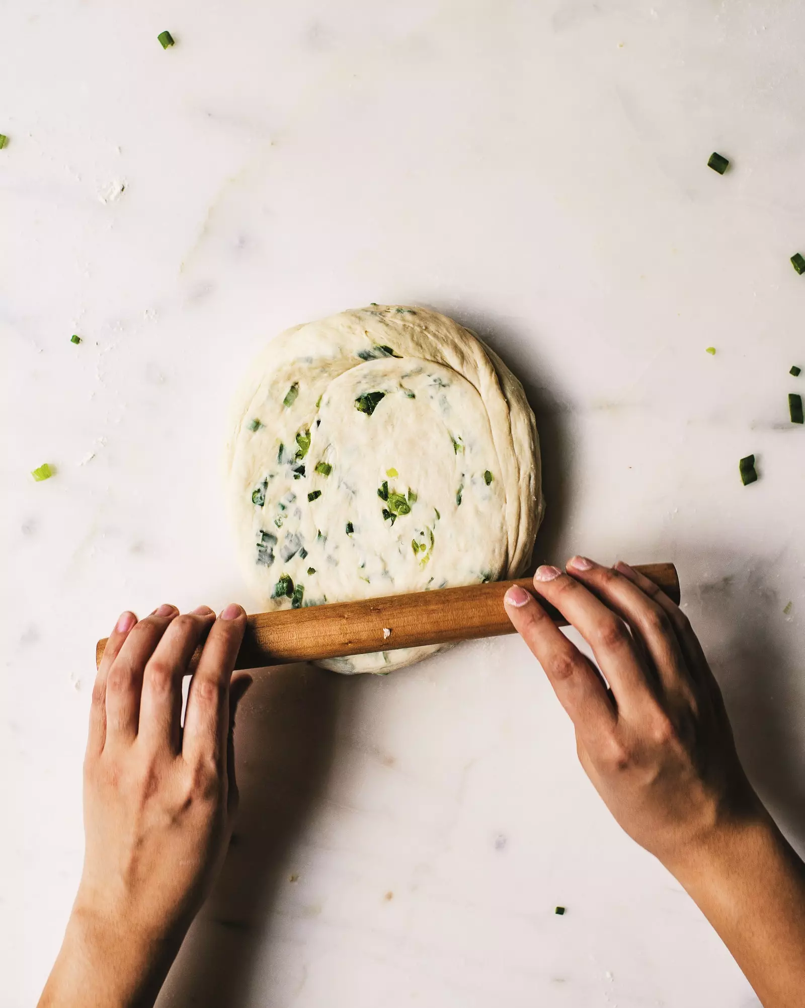 Foto fan in Yeasted Scallion en Sesam Bing daai wurdt útrôle op in moarmeren oanrjocht.