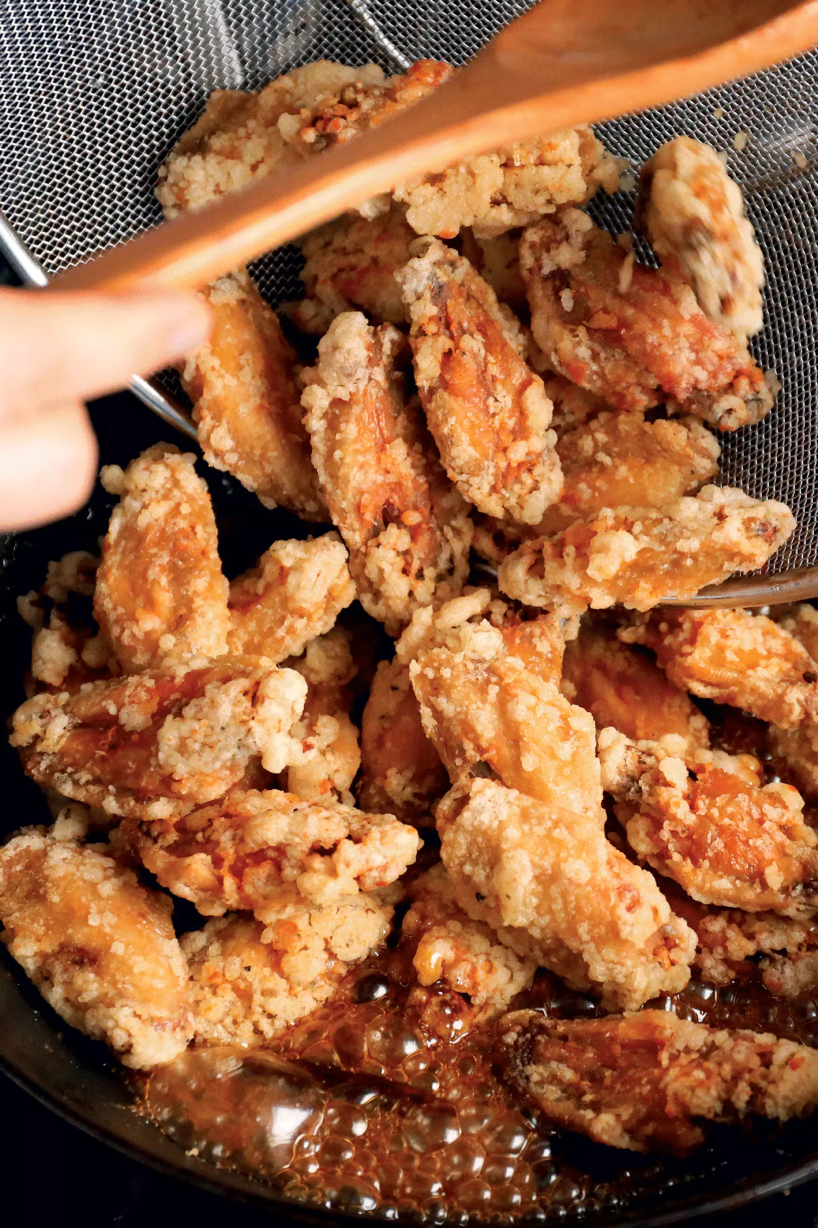 Ayam goreng Korea dari saringan menjadi panci saus bubbling.