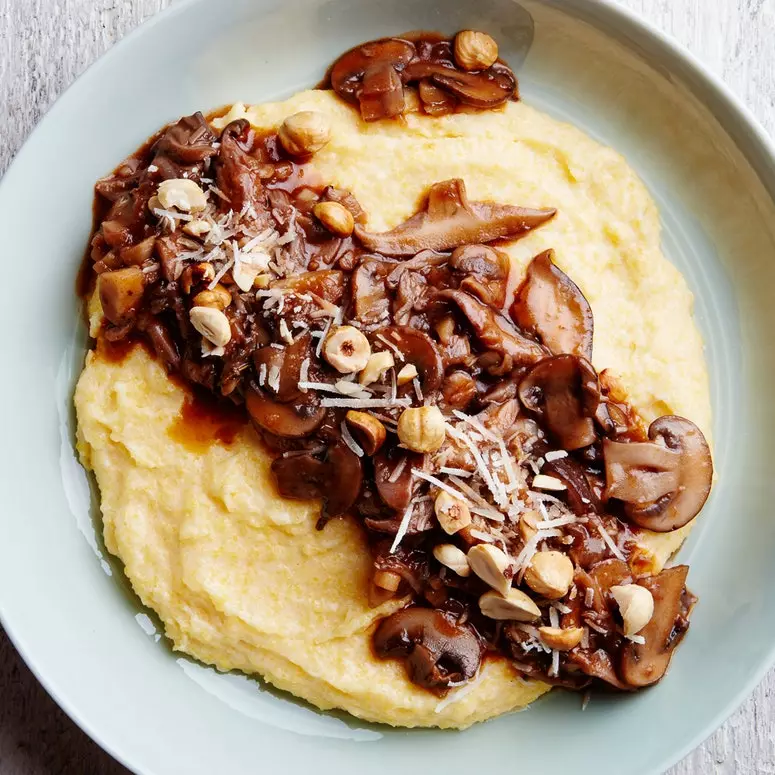 Ragú de champiñones silvestres y chirivía sobre polenta en un tazón poco profundo.