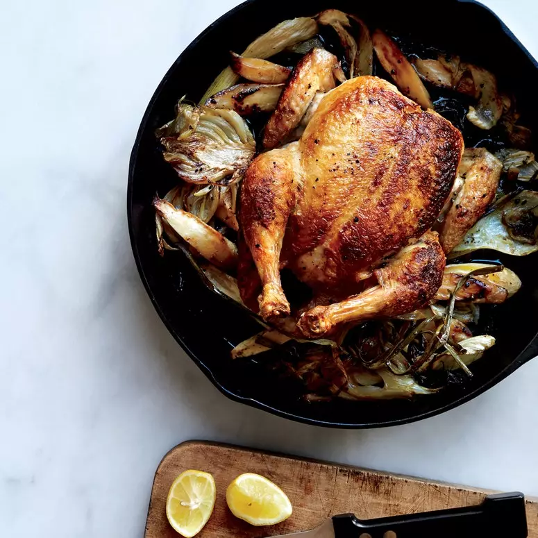 Inihaw na manok sa isang cast-iron skillet na may haras, parsnips, at scallion.