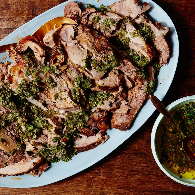 Bahu babi yang dimasak dengan lambat di piring biru dengan saus basil.