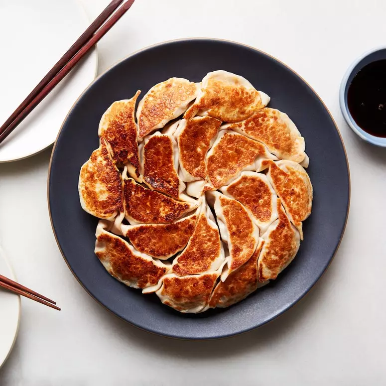 Foto af svinetofu-dumplings på en serveringsplade med te og sojasovs på siden.