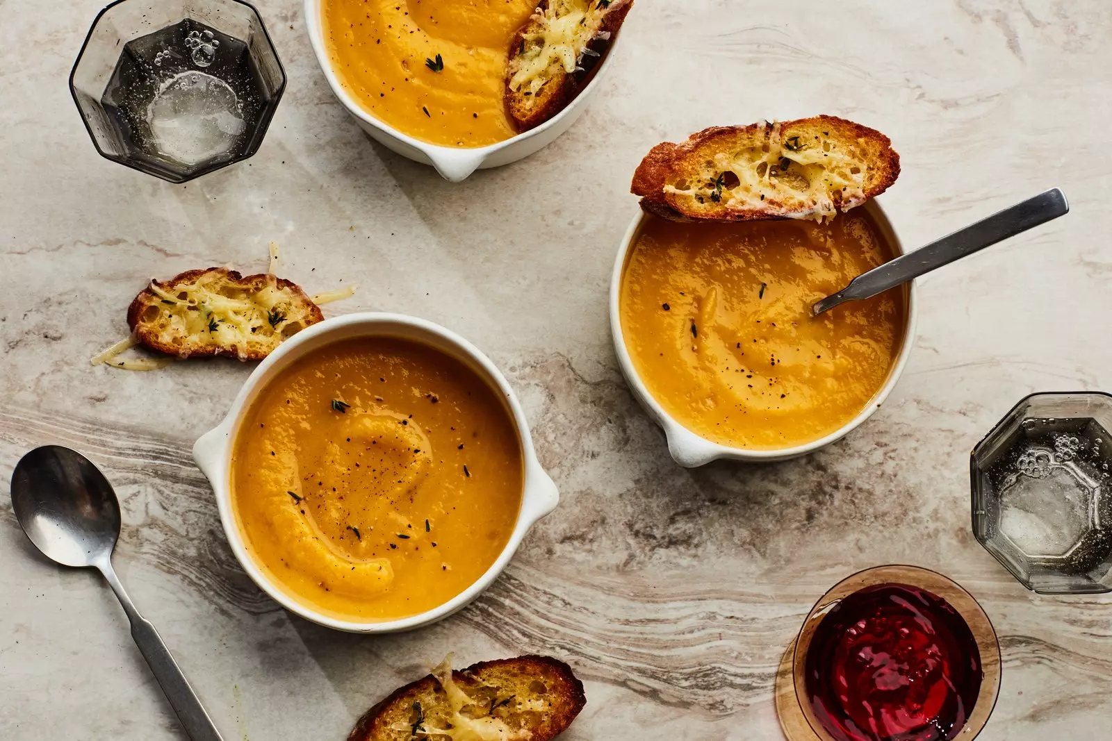 Tre skåle vintersquashsuppe toppet med Gruyère-croutoner