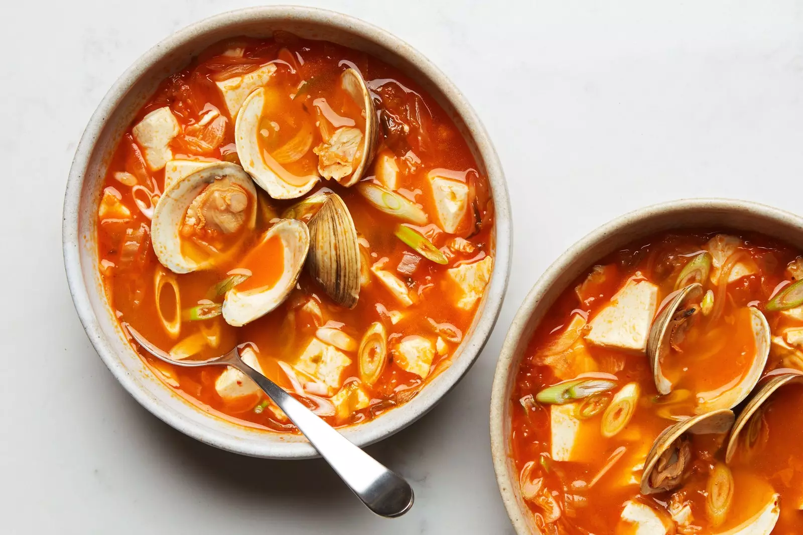 Foto von zwei Schüsseln mit Kimchi-Muscheln mit einem Löffel.