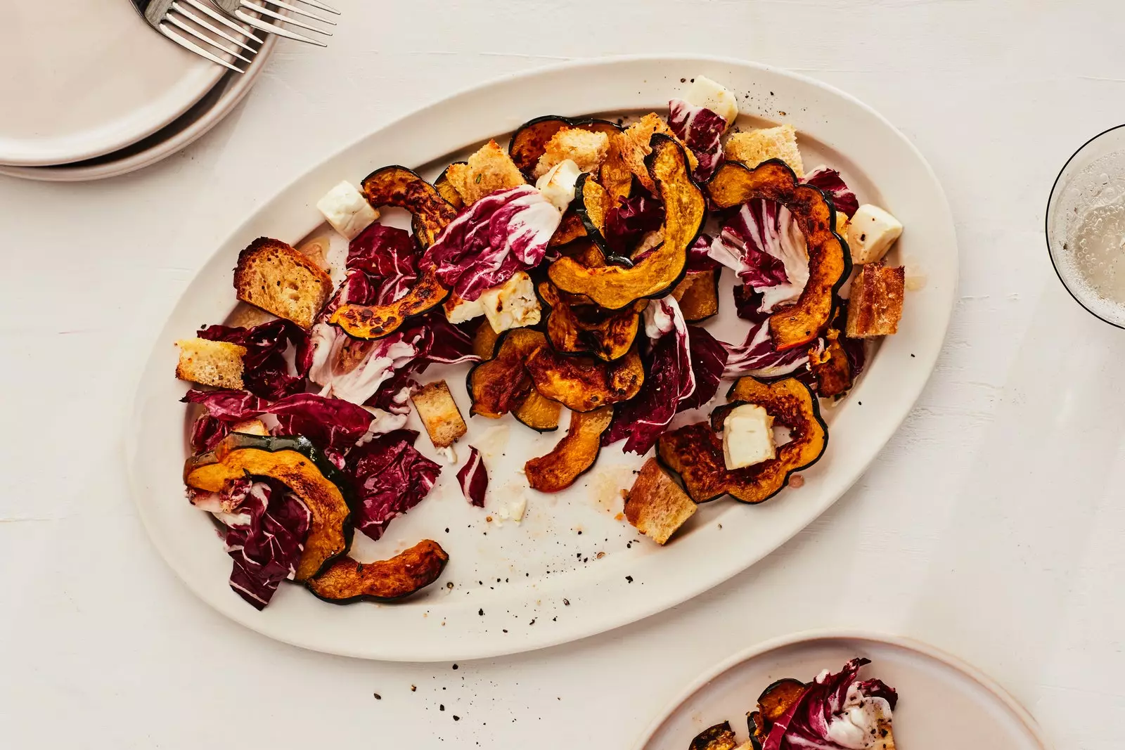 Sheetpan gerösteter Kürbis und Feta-Salat auf einem ovalen weißen Teller.