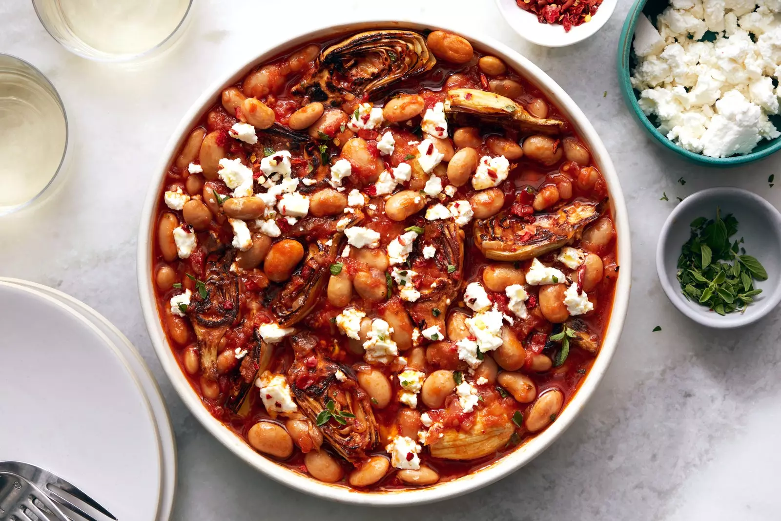 Foto von geschmorten Riesenbohnen mit Tomaten, Artischocken und Feta