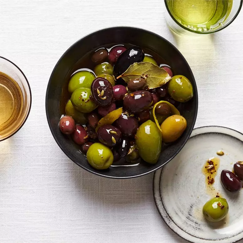 Fotografie cu un castron de măsline cu pahare de vin alb în lateral.