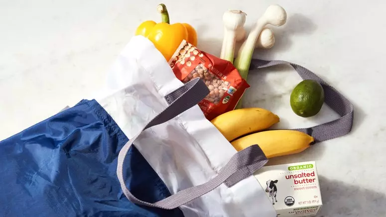 Fotografija vrećice sa žutom paprikom, lukom, vrećicom slanutka, dvije banane, limetom i kutijom maslaca.