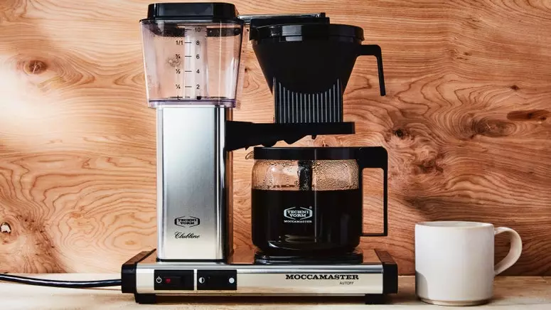 Najbolji aparat za kavu (Moccamaster) s kuhanom kavom u staklenoj posudi i šalicom uz njega.