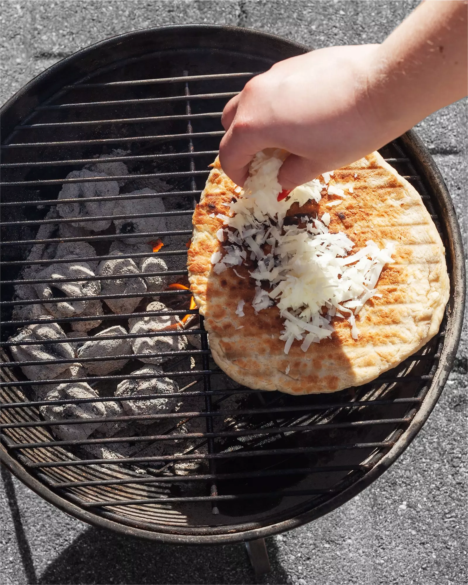 Foto de manxec repartit sobre una crosta de pizza sobre una graella de carbó.