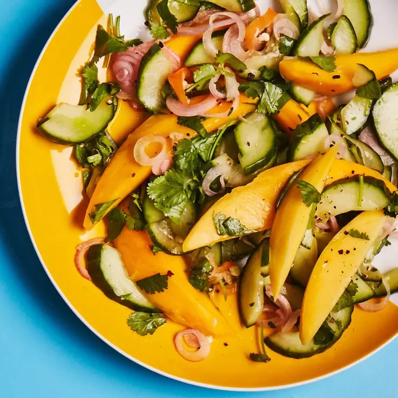 Foto af en af vores bedste mango opskrifter sprød mango og agurk chow på en tallerken med en turkis baggrund
