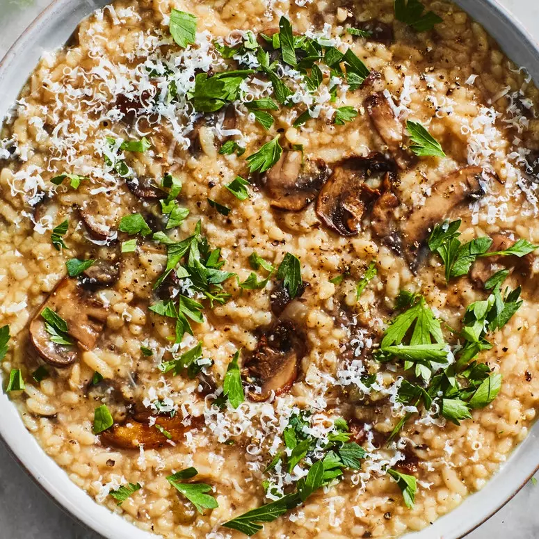 Bir piyola qo'ziqorinli risotto yangi maydanoz va maydalangan Parmesan pishloq bilan bezatilgan.