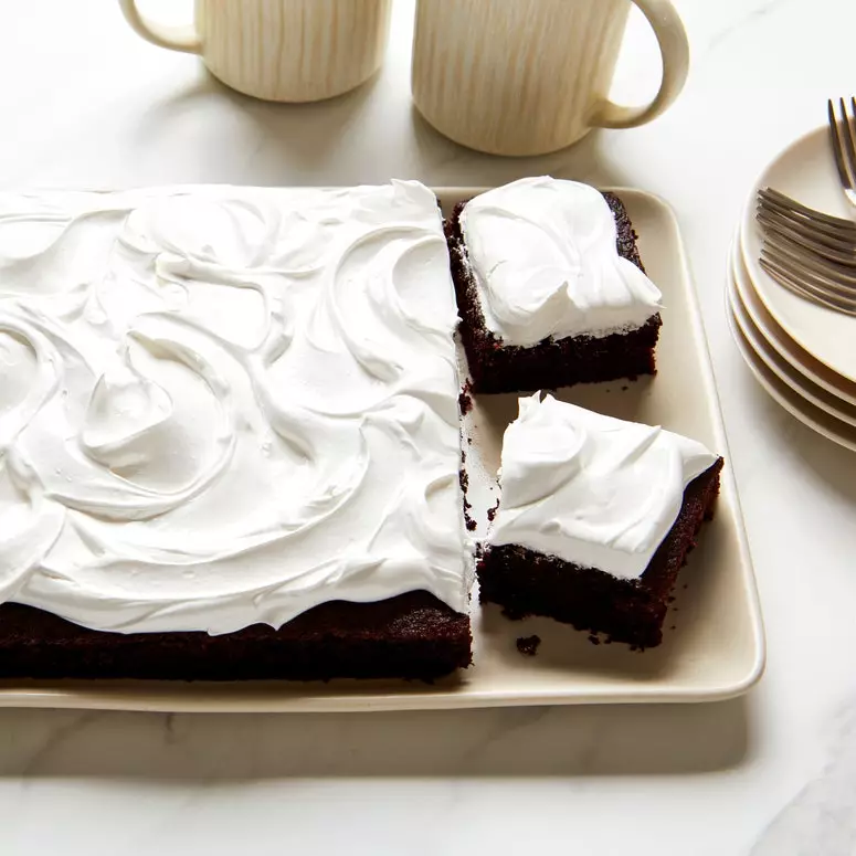 一張深黑巧克力蛋糕的照片，配上意大利蛋白酥皮，放在盤子上，旁邊放著盤子和叉子。