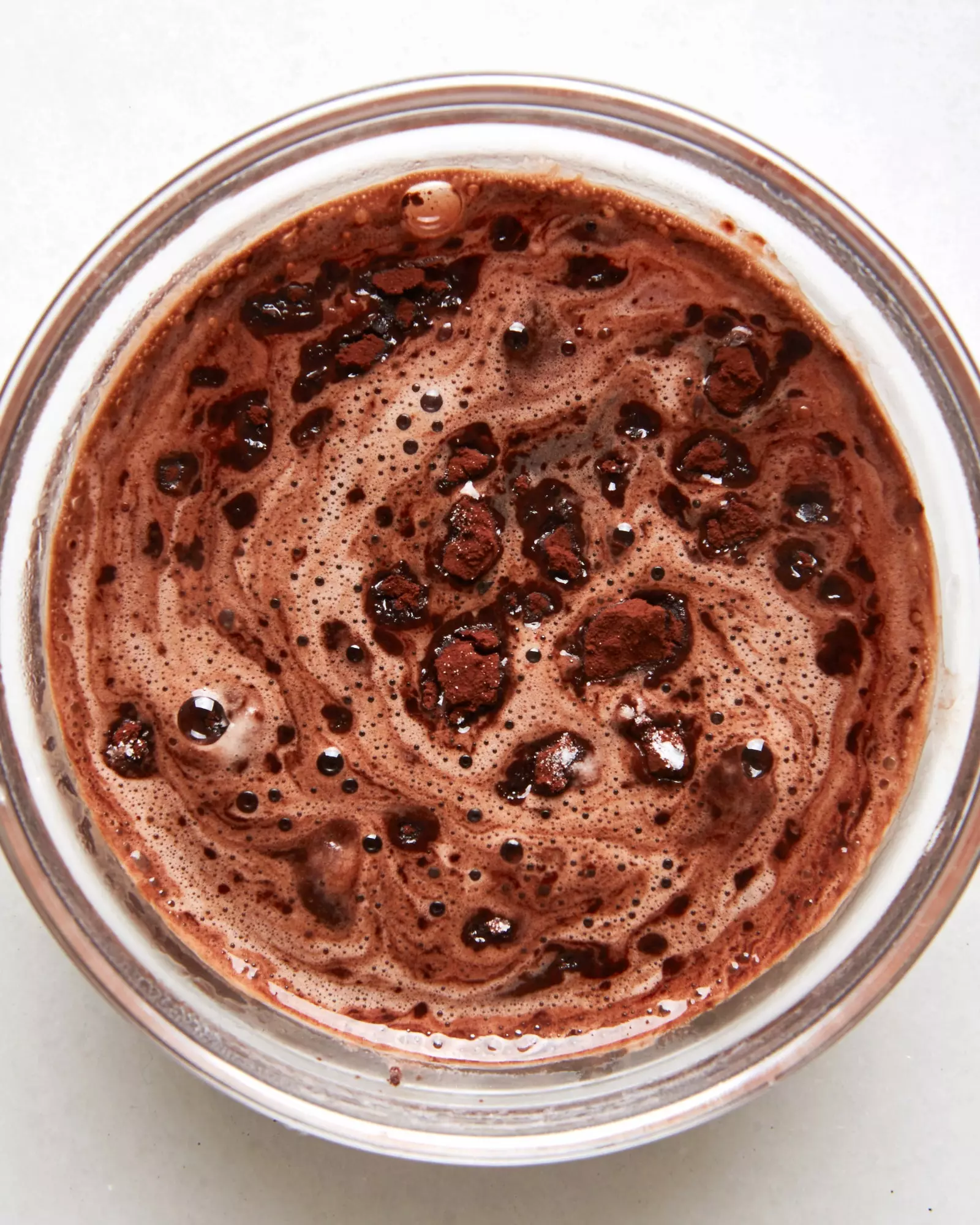Снимка на какаова вода на прах и сода за хляб, смесени заедно в стъклена купа.