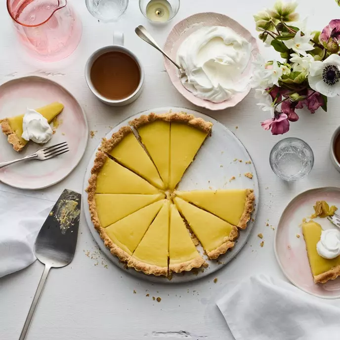 Tarta de cuajada de limón con dos rebanadas eliminadas junto con platos para servir.