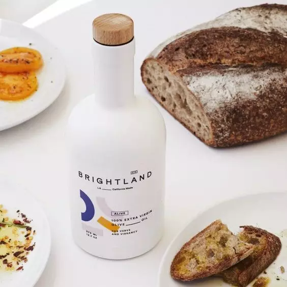 Foto de Alive Olive Oil de Brightland sobre una mesa con una hogaza de pan.