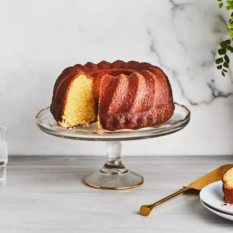 Kekê Lemon Bundt li ser stûnek cake zelal.