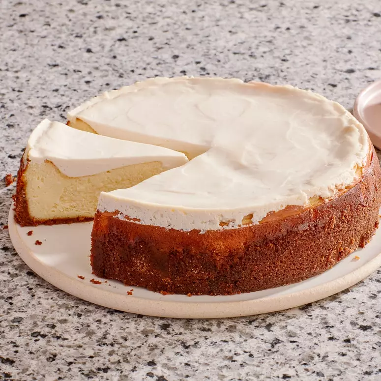 એક સ્લાઇસ પર એક સ્લાઇસ પર એક ટુકડો creamtopped cheesecake ત્રણ કારીગરોનો જથ્થો એક પ્લેટ અને બીજી સ્લાઇસને દૂર કરે છે ...