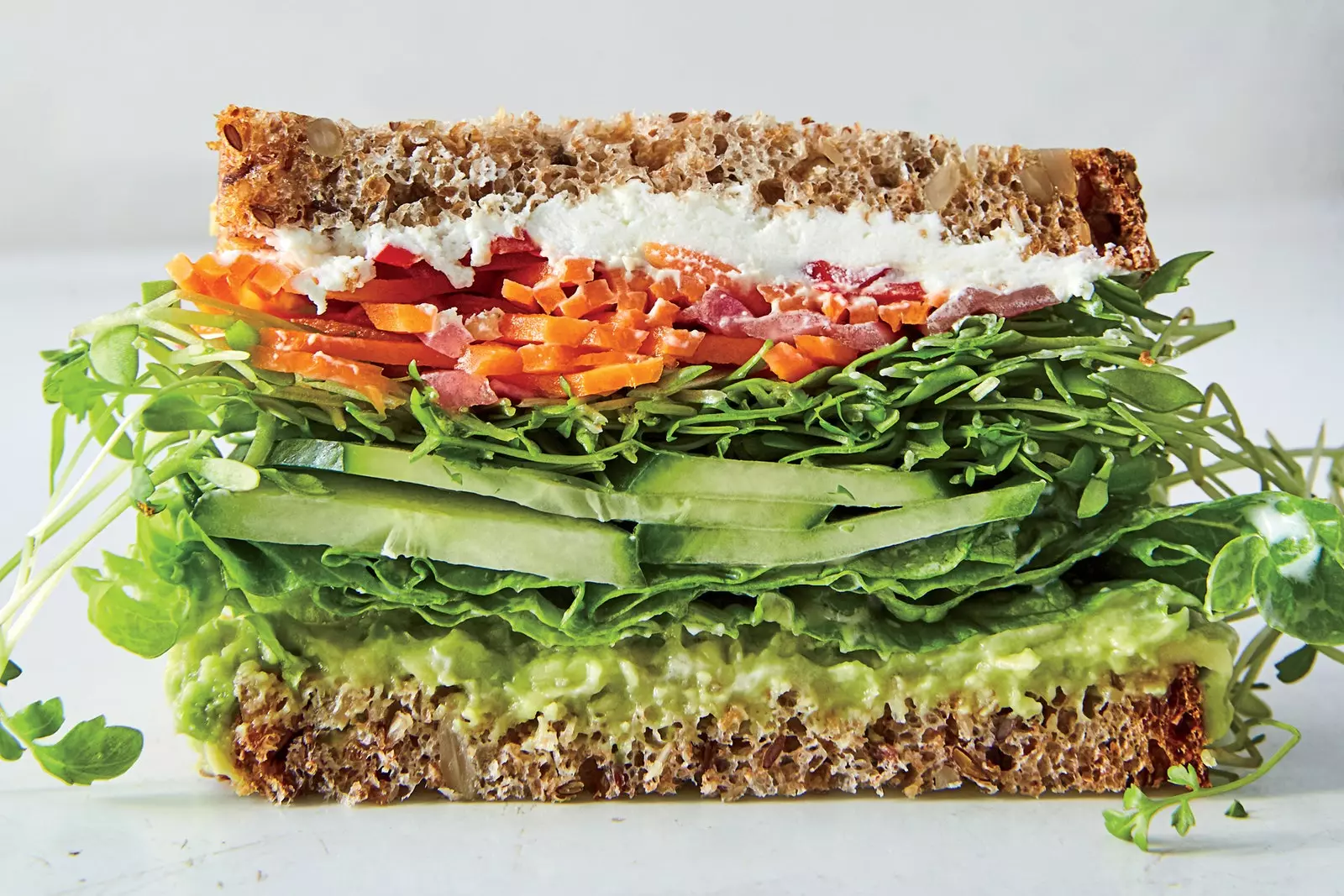 Crosssection ta 'sandwich b'ħobż qalb imfarrak avokado ħjar sprouts ħass karrotti mqatta' fin u krema...