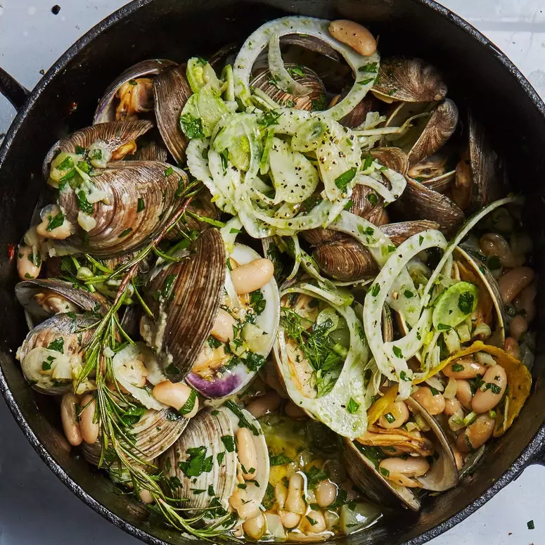 Vongole in salsa di fagioli bianchi in una pentola a due manici.