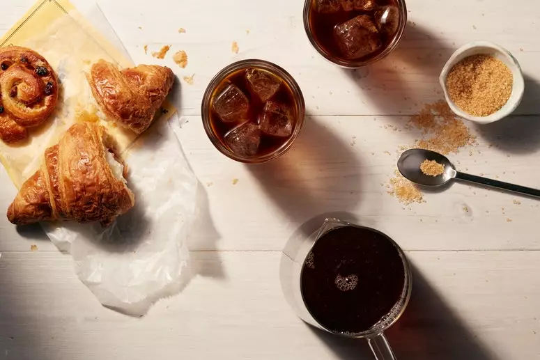 Kuva kylmävalmisteisesta kahvista leivonnaisten ja kulhollisen sokerin kera.