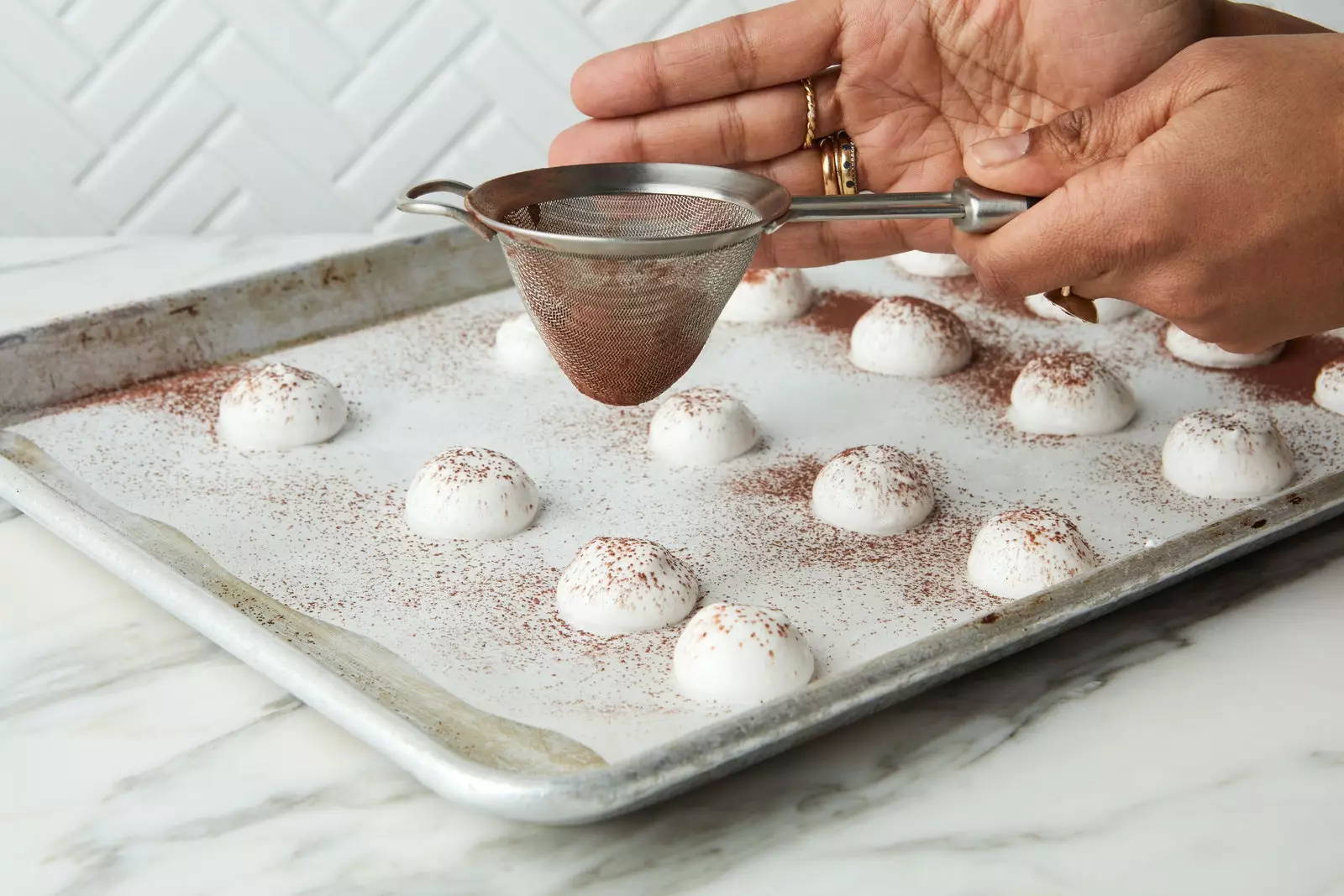 Setšoantšo sa motho ea tšelang li-mushroom tsa meringue ka phofo ea cocoa.