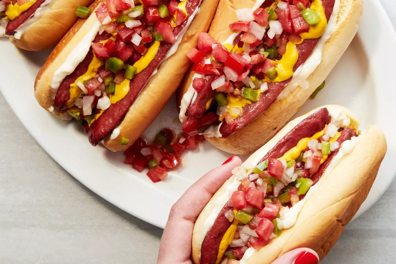 fotografija ruke koja uzima hot dog u argentinskom stilu sa tanjira
