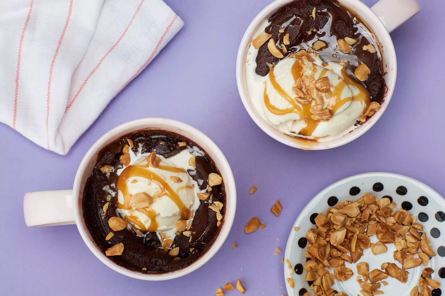 To kaffekrus fyldt med chokoladekage, der er blevet toppet med vaniljeis og et karameldryp.