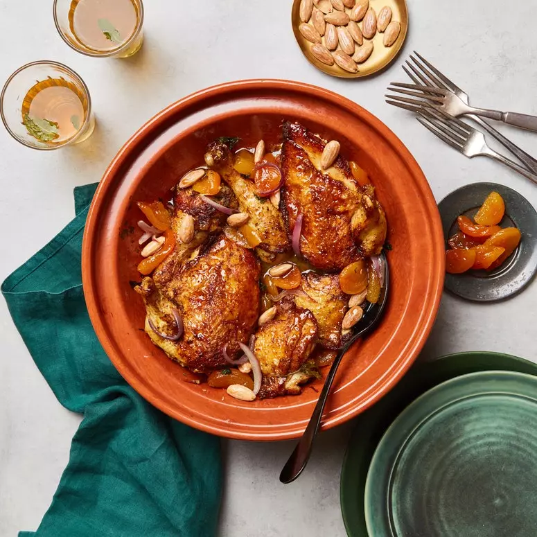 Gourmets kyllingetagine med abrikoser og mandler i en taginegryde med myntete og mandler på siden.