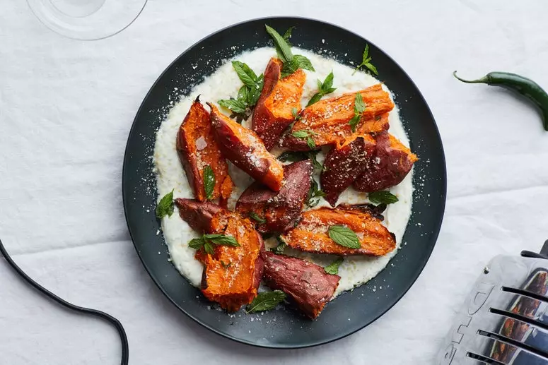 Pezzetti di patata dolce arrosto strappati su un letto di yogurt conditi con menta fresca e semi di sesamo schiacciati.