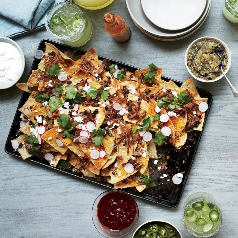 Foto af en bakke med nachos til en af vores yndlings nacho-opskrifter toppet med bønner, radiseskiver koriander.