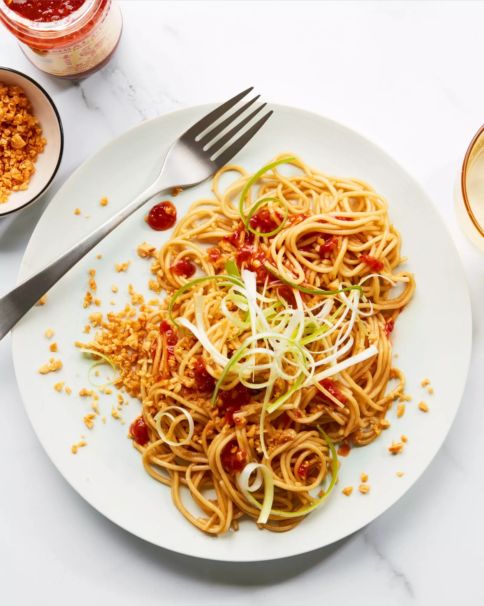 Setšoantšo sa poleiti ea li-noodle tsa konofolo e nang le fereko e nang le sekotlolo sa konofolo e halikiloeng e halikiloeng le peista ea chilisi ka thōko.