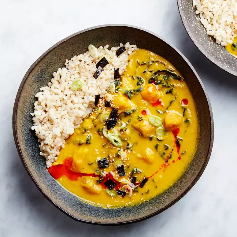 En af de bedste veganske middagsopskrifter squashsuppe og brune ris i en keramisk skål.
