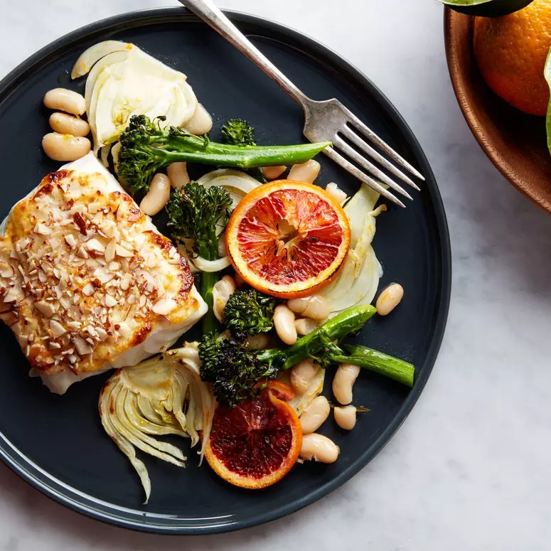 Morue grillée au fenouil et à l'orange sur une assiette bleu foncé avec une fourchette.