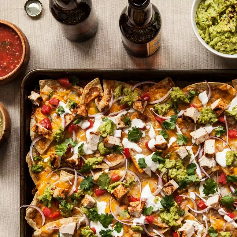 Fotografija našega recepta za nachos s stranskimi skledami zelene salso rdeče salse in guacamole.