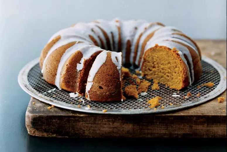 Pumpkin spice bundt cake na nilagyan ng puting icing sa isang cooling rack.