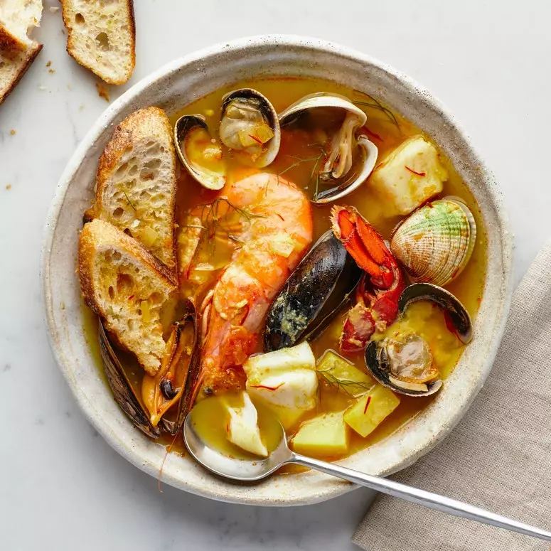 Ang resipe sa Bouillabaise sa Gourmet sa usa ka panaksan nga adunay usa ka kutsara nga adunay mga hiwa sa pan sa kilid.