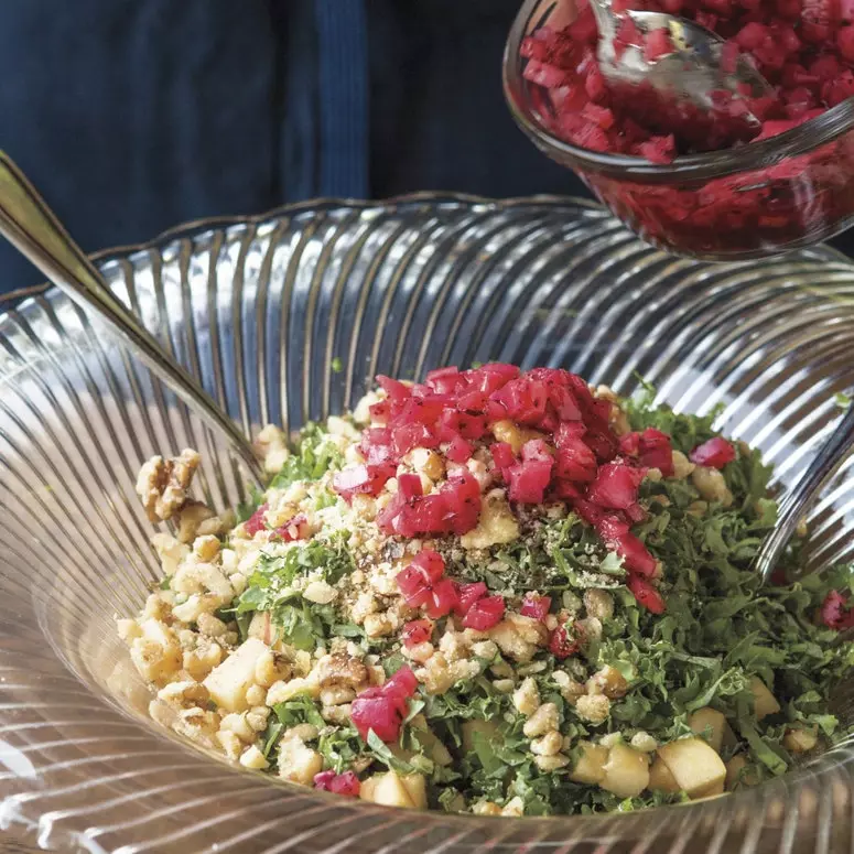 Ntshiab iav lub tais ntawm tabbouleh nrog kale txiv apples walnut thiab sumac nrog ob hlau khoom siv.