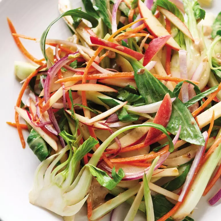 Salad apụl na bok choy dị ọhụrụ na efere ọcha.