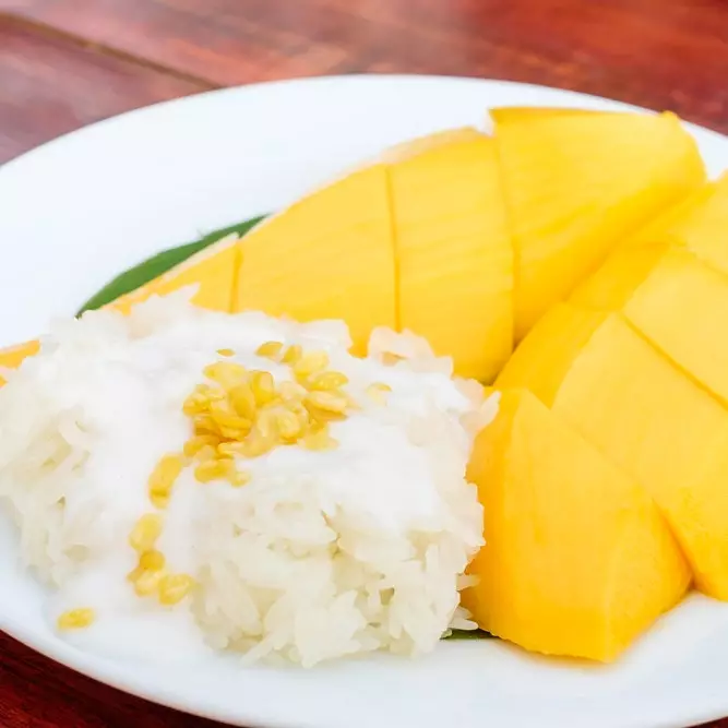 Viipaloitu mango ja tahmea riisi lautasella.