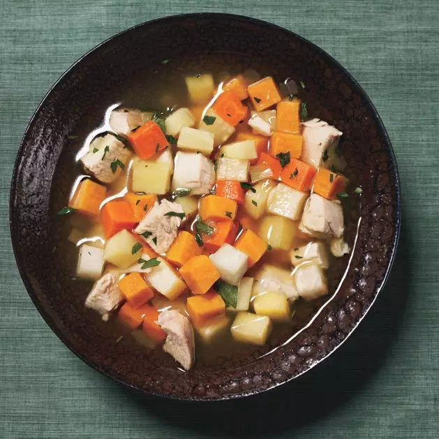 Poto mangkok hideung sareng sup hayam di jerona kalebet sayuran akar cubed.