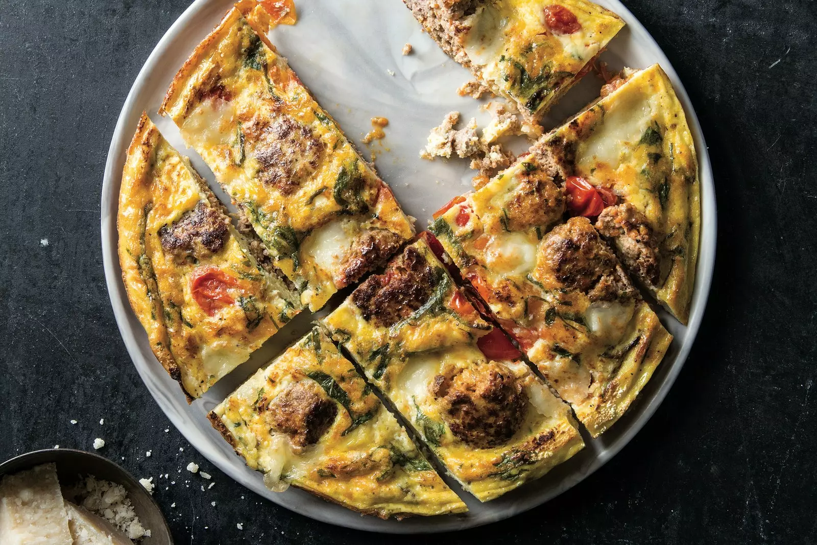 Frittata ya pande zote iliyokatwa kwenye wedges nane kama bar.